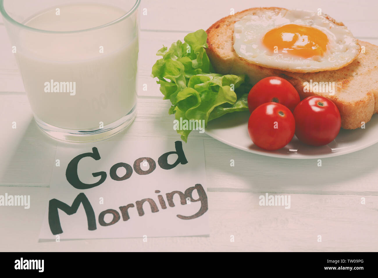 Note with written phrase GOOD MORNING and tasty breakfast on table ...
