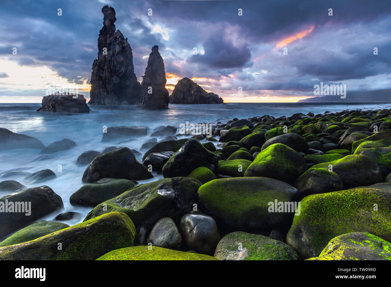 Seascape with giant rocks in the ocean at dawn and green stones beach ...