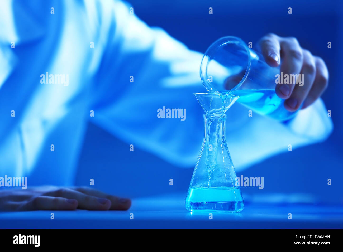Scientist pouring sample into a test flask, closeup Stock Photo - Alamy
