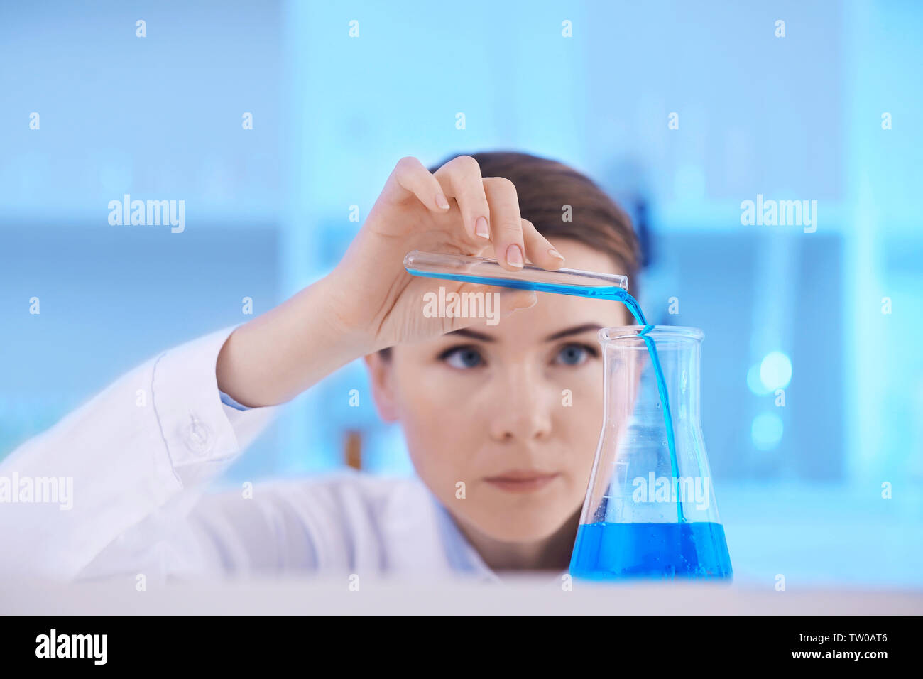Scientist pouring a sample into a test flask Stock Photo - Alamy