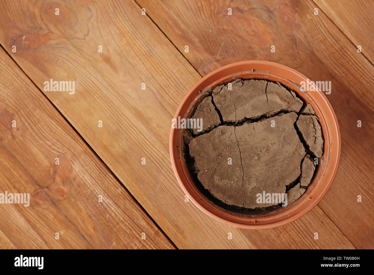 Water shortage concept. Pot with dry soil on wooden background Stock ...