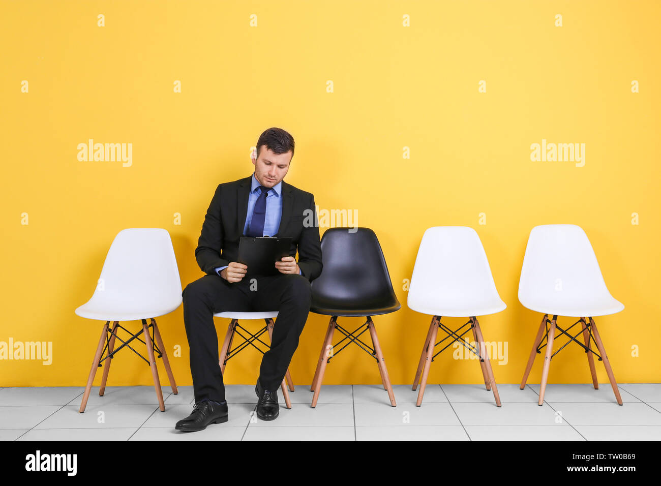 Young man waiting for job interview on yellow wall background Stock ...