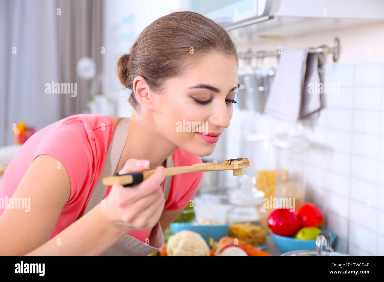 Cooking concept. Young woman tasting food Stock Photo - Alamy