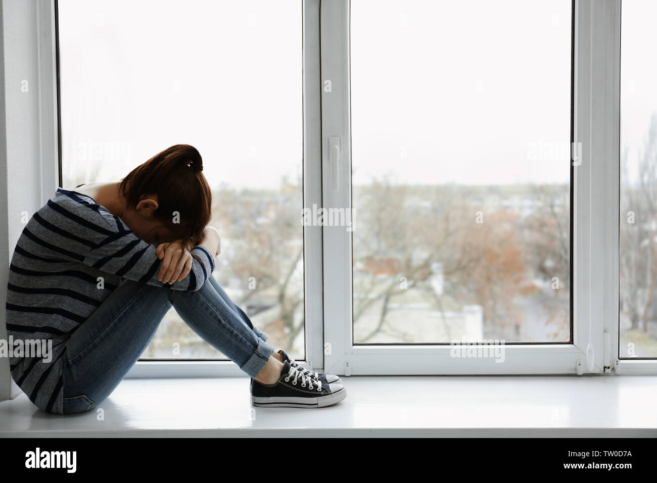 Little girl crying on windowsill Stock Photo - Alamy