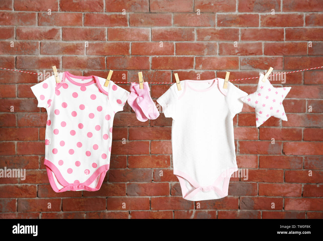 Clothesline with hanging baby clothes on dark brick-wall background ...