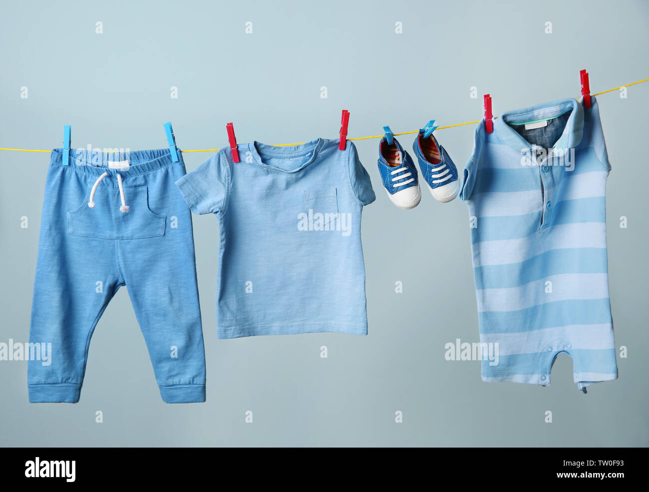 Clothesline with hanging baby clothes on grey background Stock Photo ...