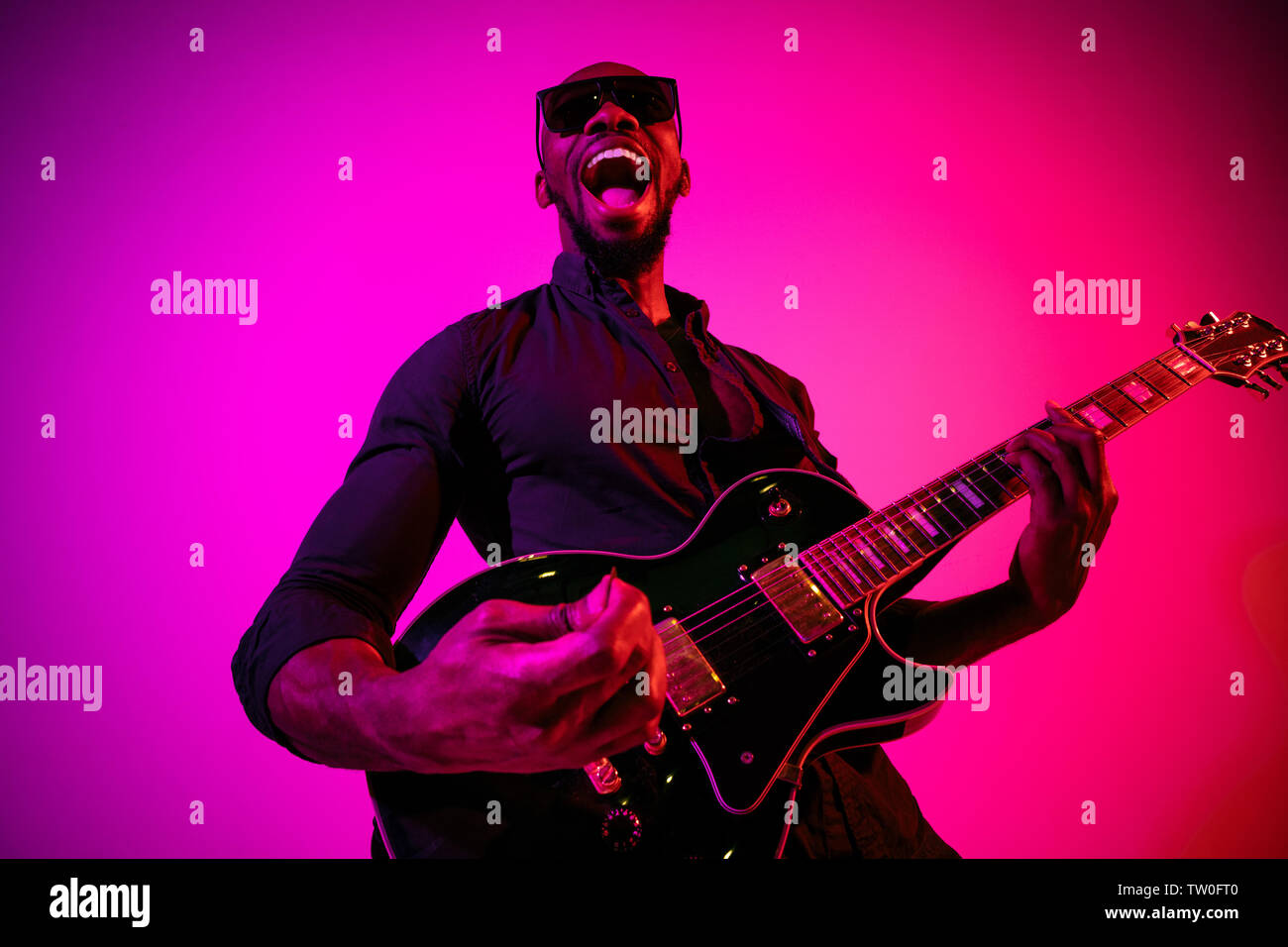 Young african-american musician playing the guitar like a rockstar on ...