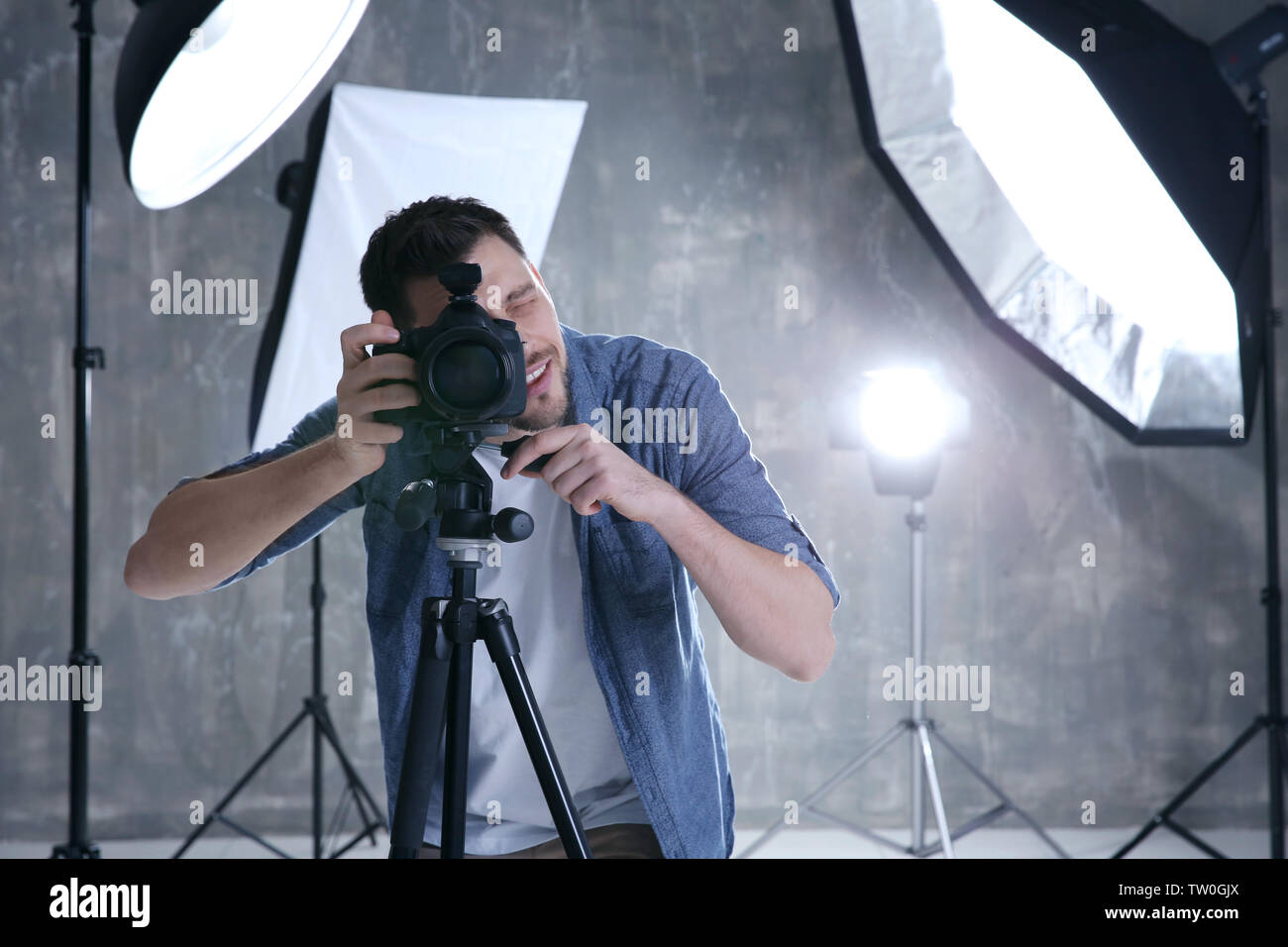 Young male photographer in studio with professional lighting equipment ...