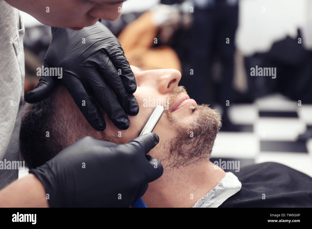Hairdresser shaving client in barbershop Stock Photo - Alamy