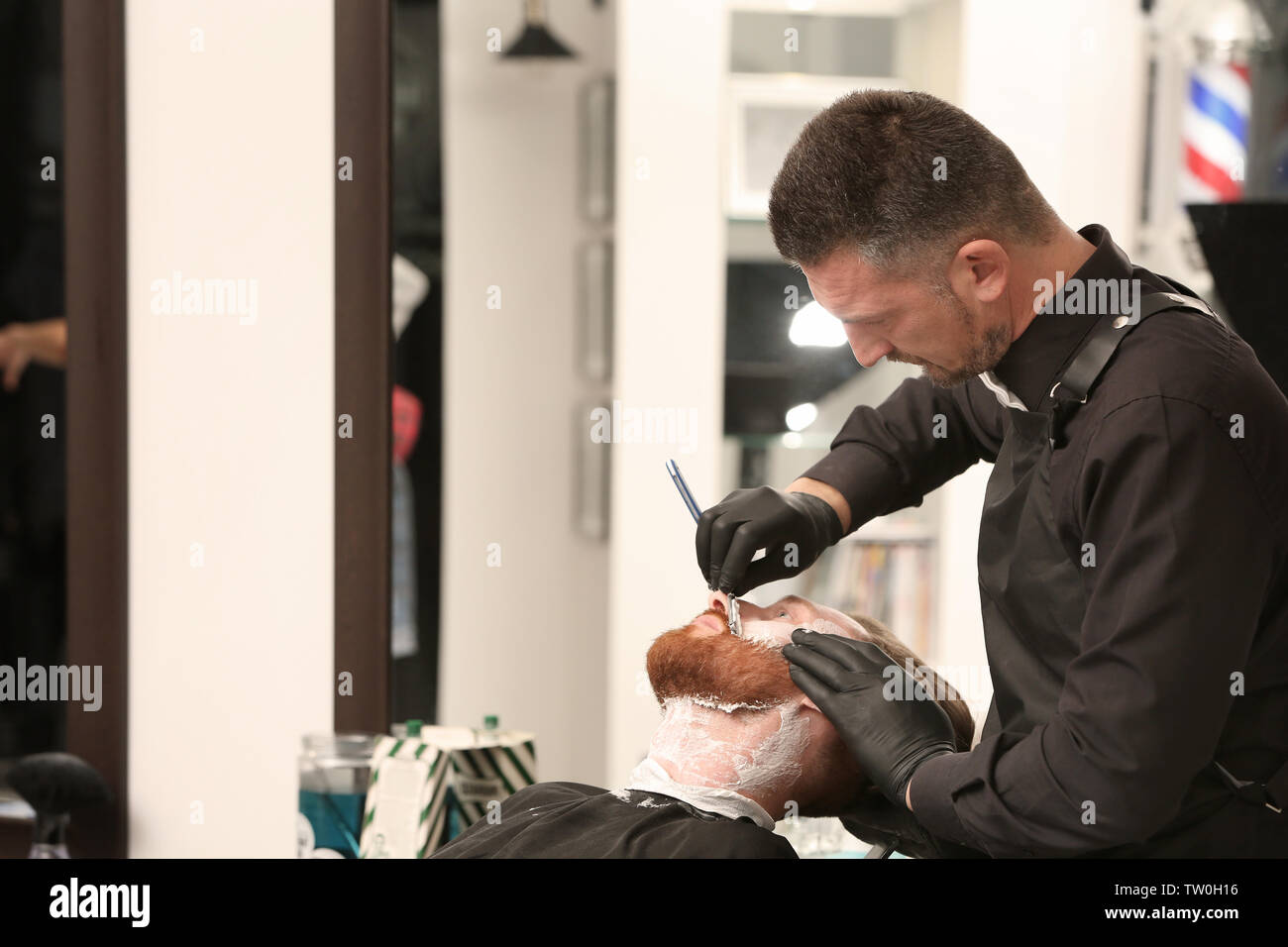 Hairdresser shaving client in barbershop Stock Photo - Alamy