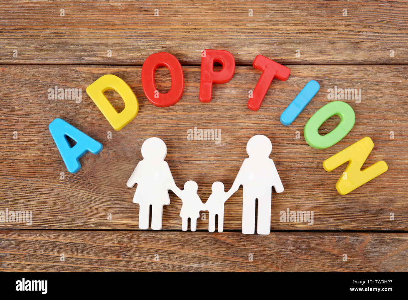Word ADOPTION and figure in shape of happy family on wooden background ...
