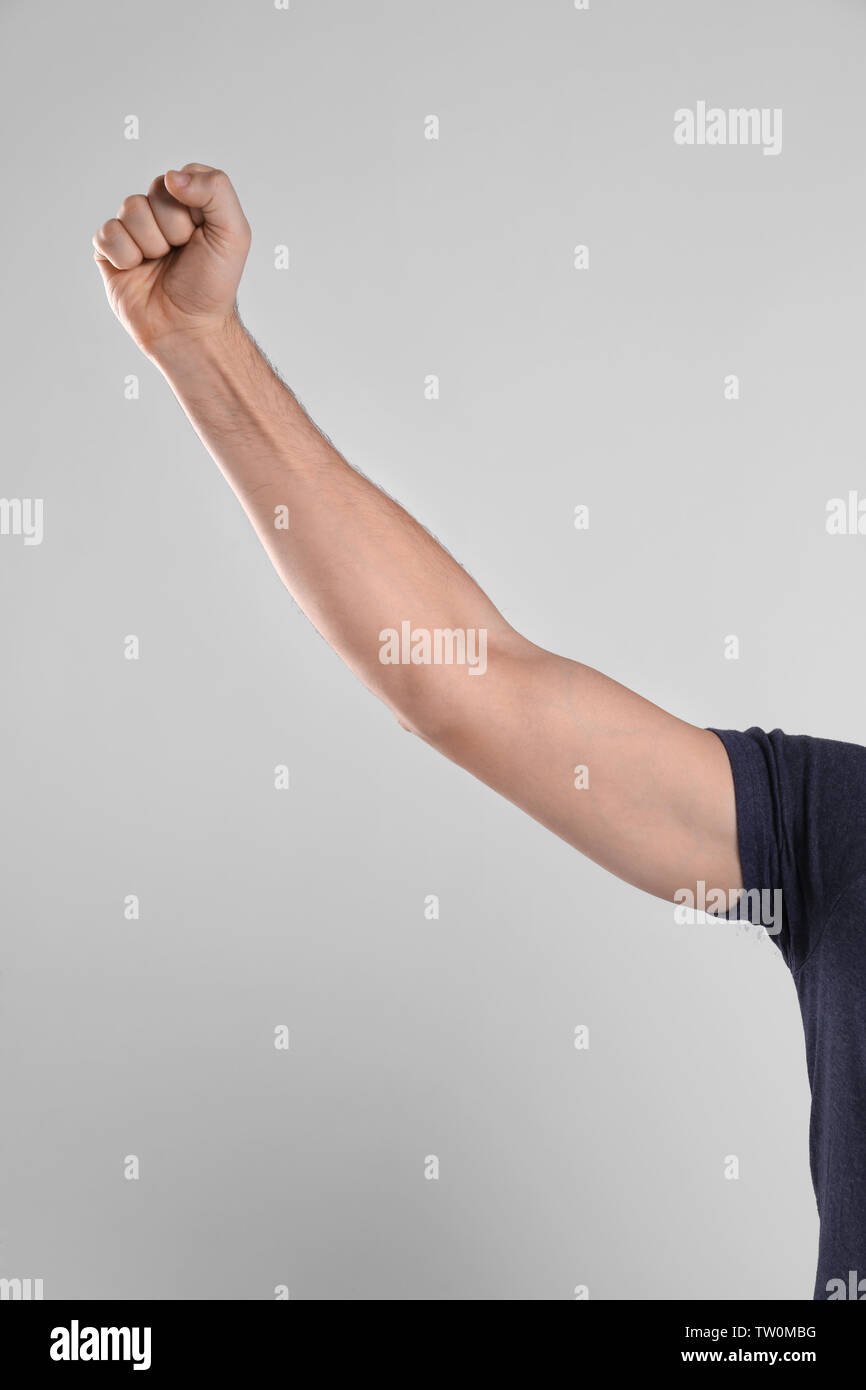 Raised male hand with clenched fist on light background Stock Photo - Alamy
