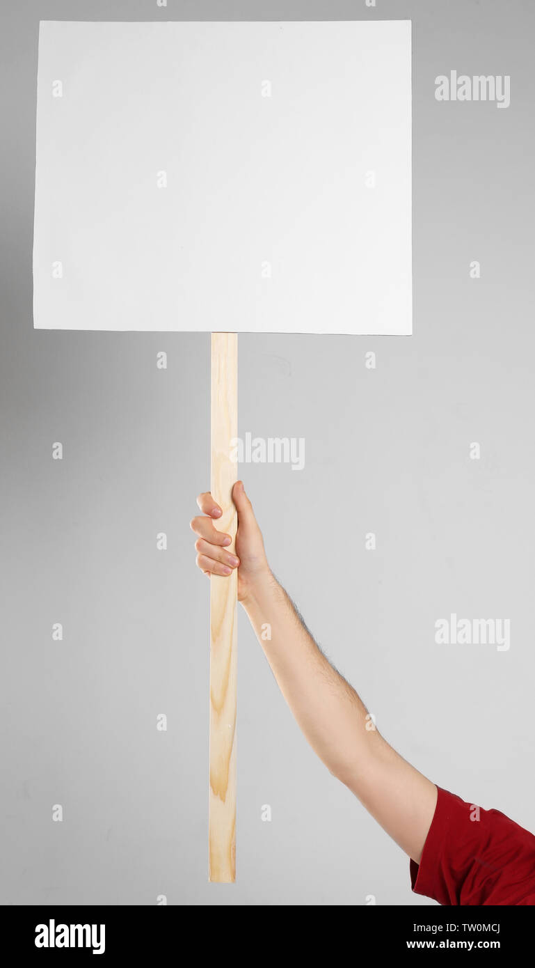 Male hand holding blank banner on wooden stick against light background ...
