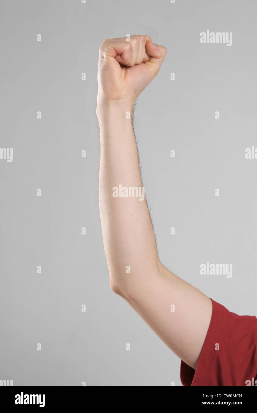 Raised male hand with clenched fist on light background Stock Photo - Alamy