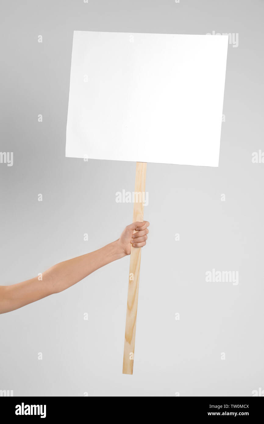 Male hand holding blank banner on wooden stick against light background ...
