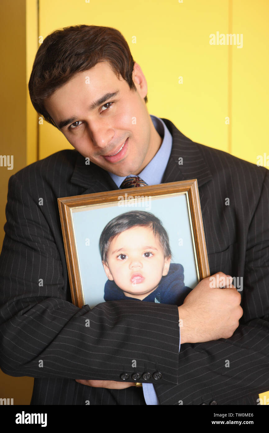 Portrait of a businessman hugging a photo frame of his son Stock Photo ...