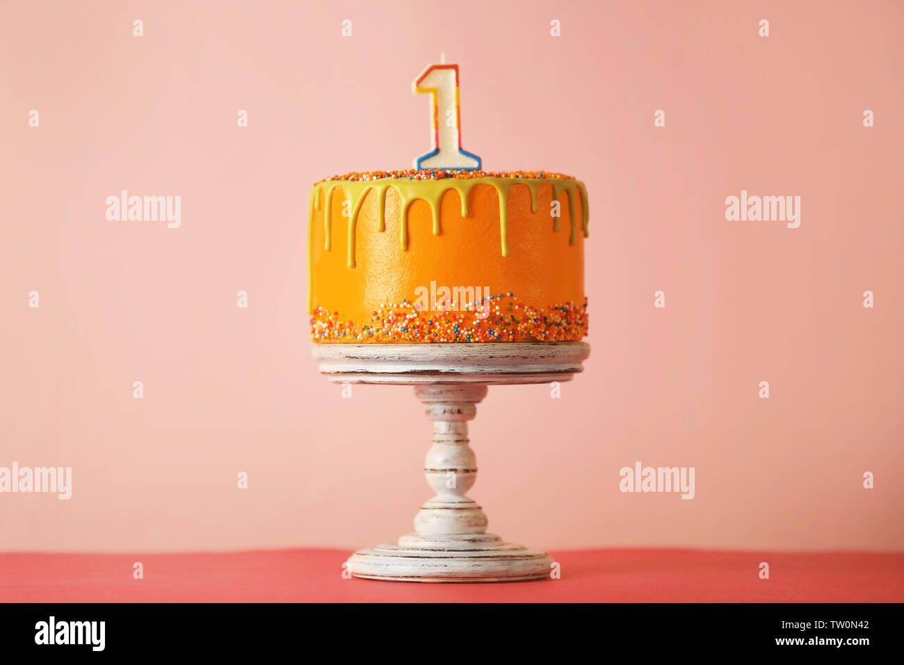 Birthday cake with one candle on pink background Stock Photo - Alamy