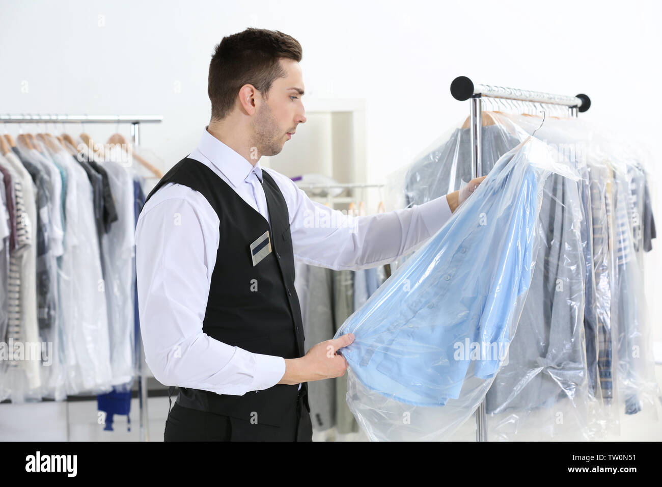 Young man working in dry-cleaning salon Stock Photo - Alamy