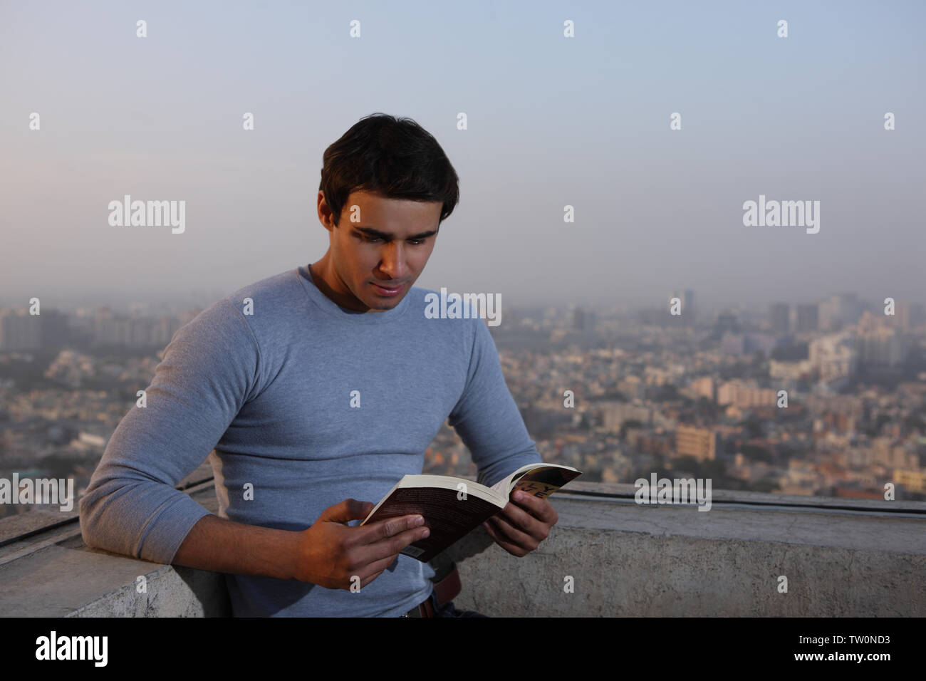 Man reading a book in a balcony Stock Photo - Alamy