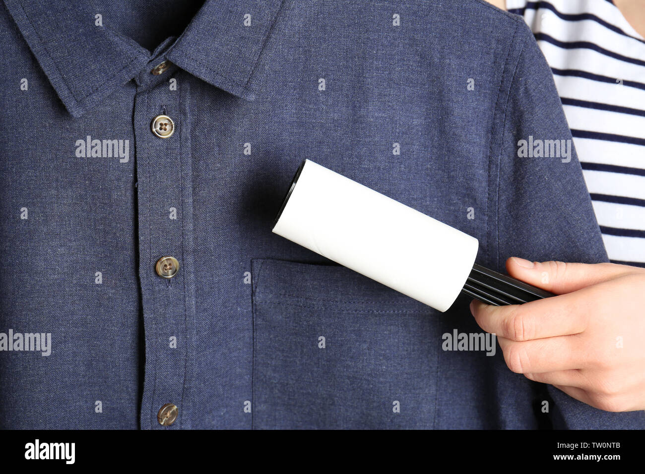 Woman cleaning shirt with adhesive roller Stock Photo - Alamy