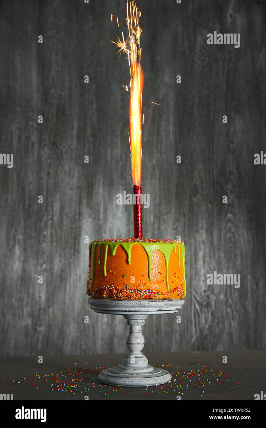 Tasty birthday cake with firework on wooden background Stock Photo - Alamy