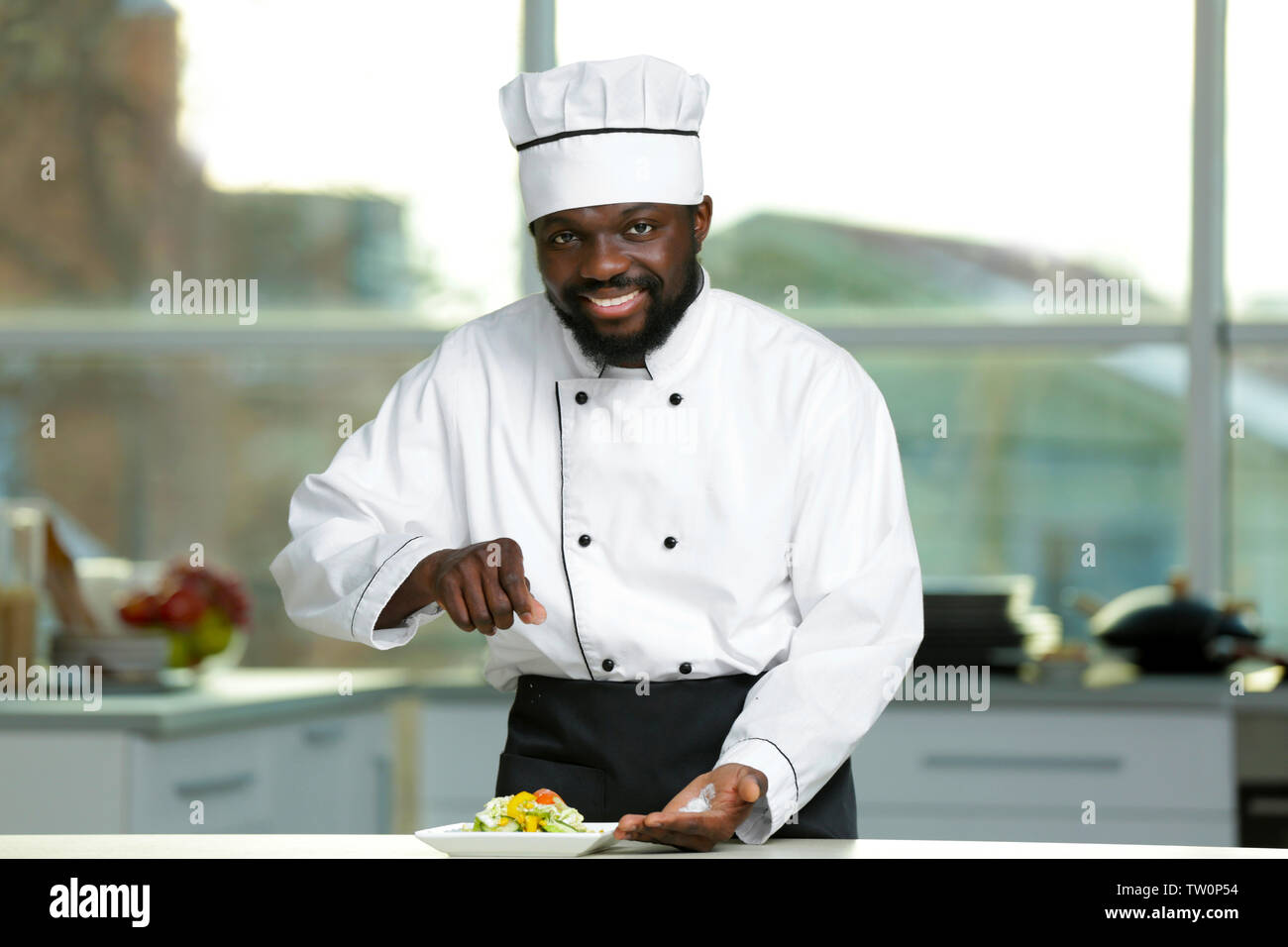 African American chef salting tasty salad in kitchen Stock Photo - Alamy