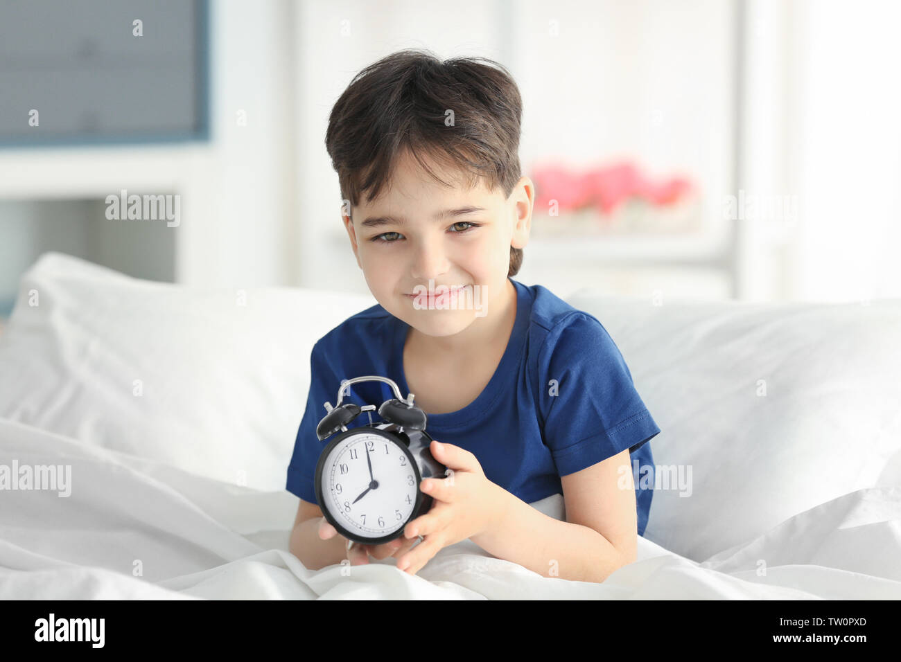 Cute little boy with alarm clock in bed Stock Photo - Alamy