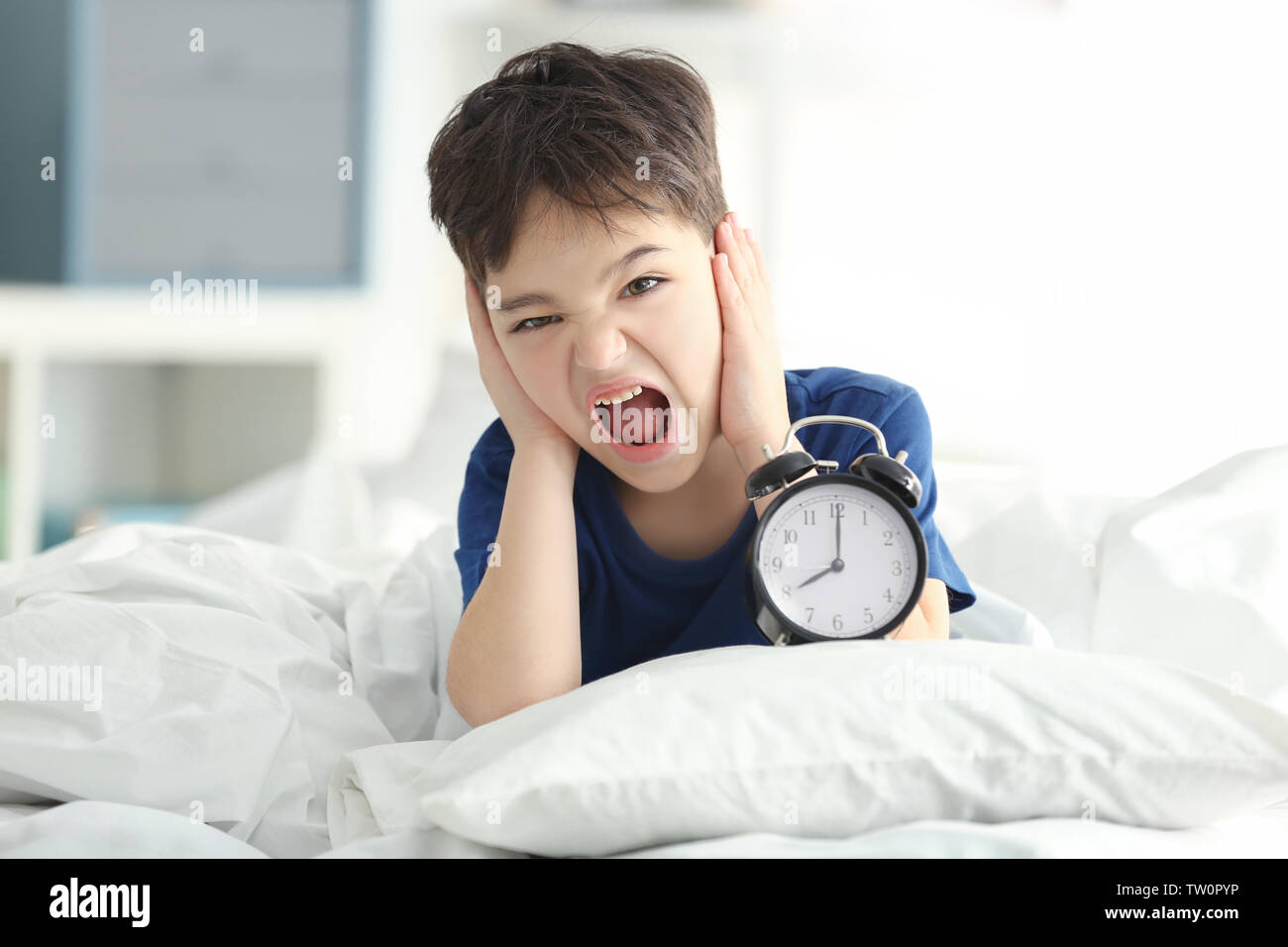 Cute little boy with ringing alarm clock in bed Stock Photo - Alamy