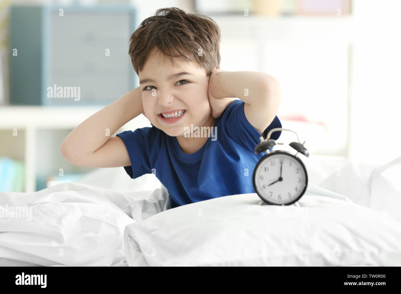 Cute little boy with ringing alarm clock in bed Stock Photo - Alamy
