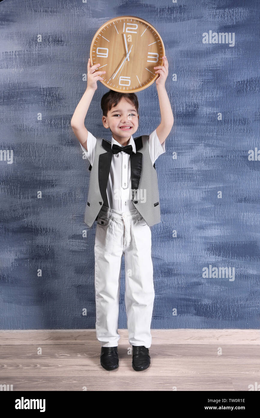 Cute little boy with big clock near color wall Stock Photo - Alamy