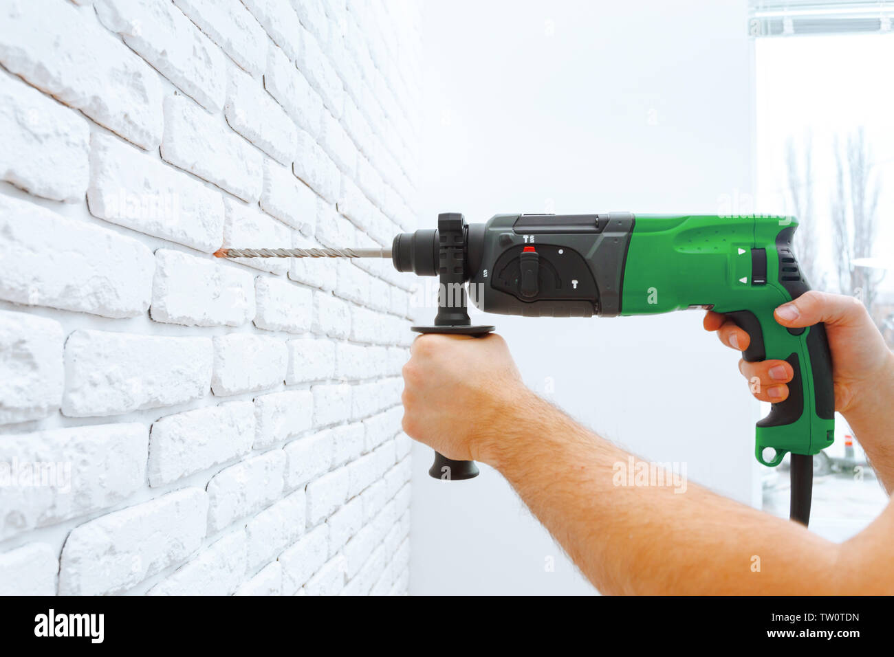 Use hammer drill to drill the wall Stock Photo - Alamy