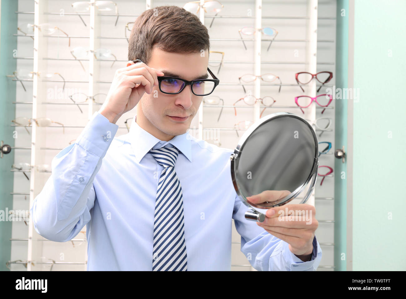 Handsome young man trying on new glasses in shop Stock Photo - Alamy