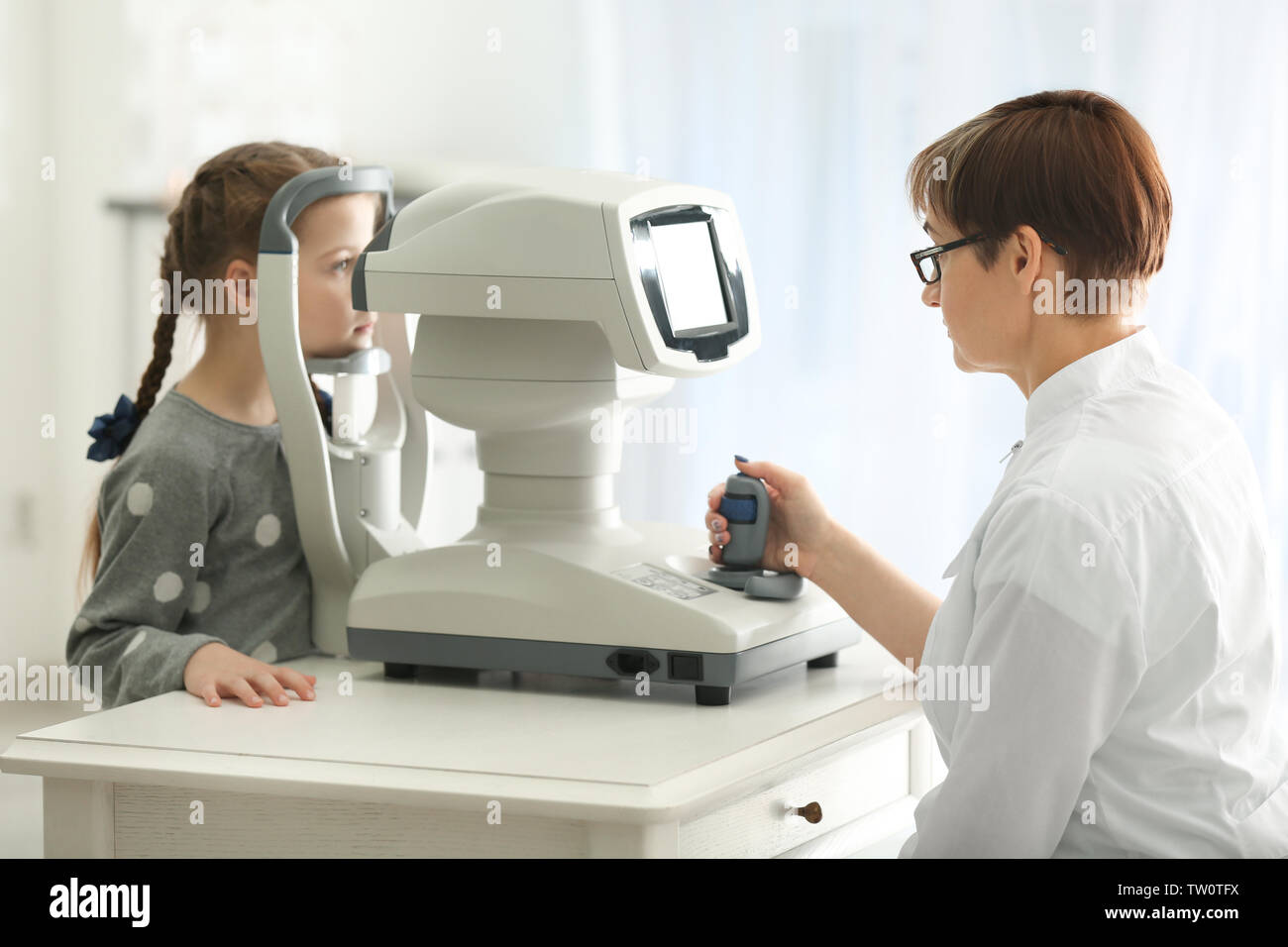 Ophthalmologist measuring intraocular pressure of little girl in clinic ...