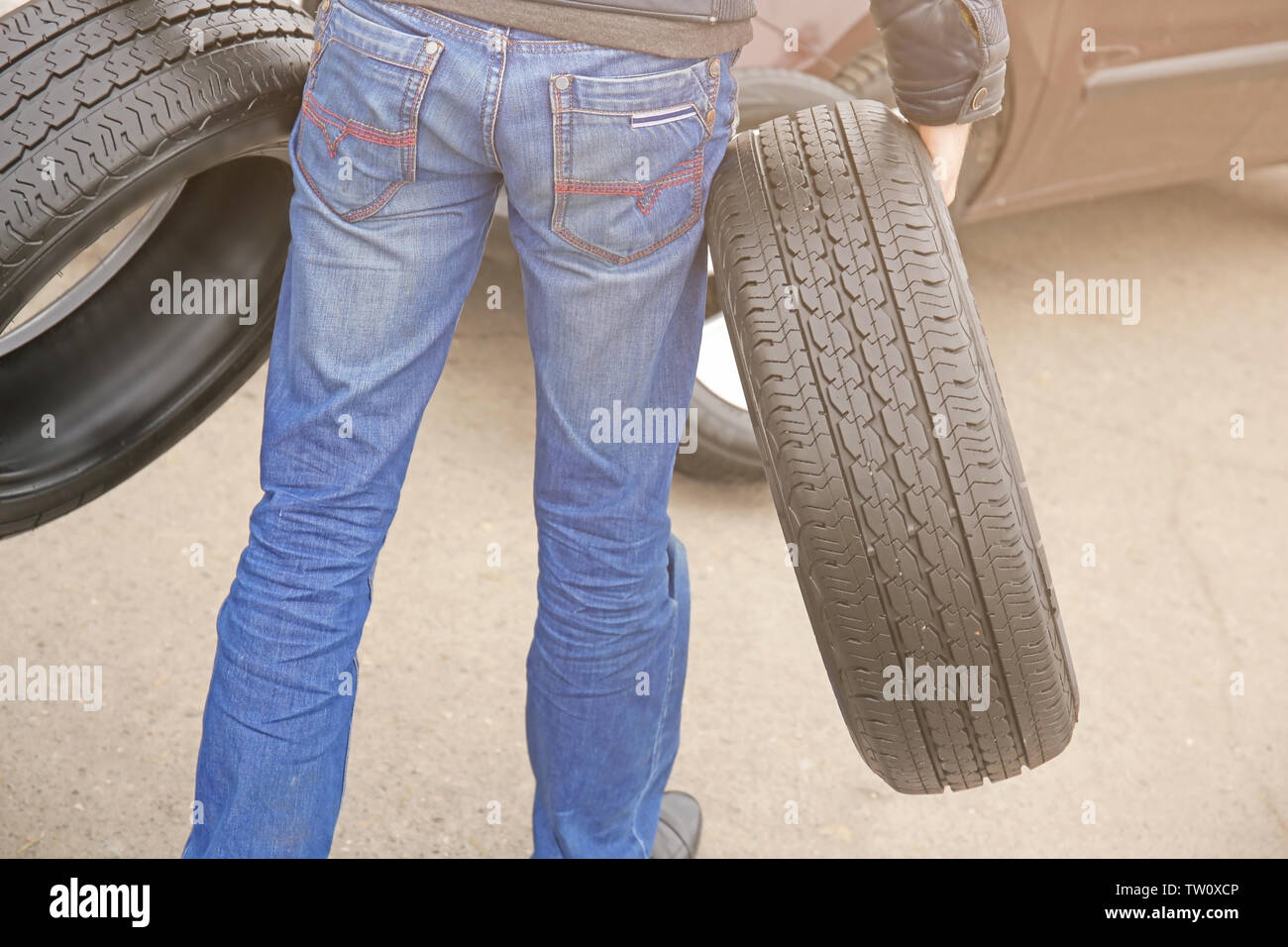 Back view of man carrying two tires outdoors Stock Photo - Alamy