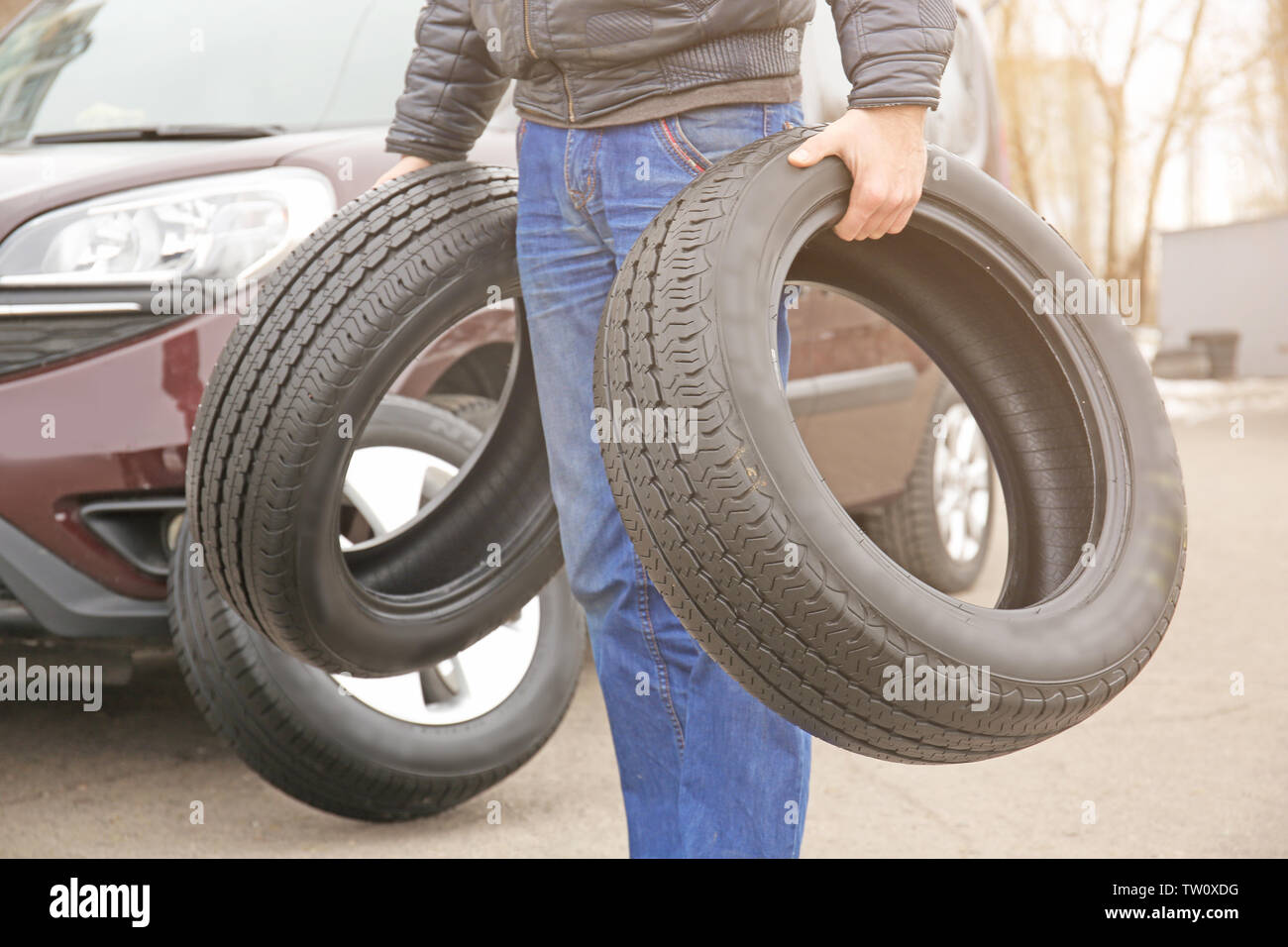 Man carrying two tires outdoors Stock Photo - Alamy