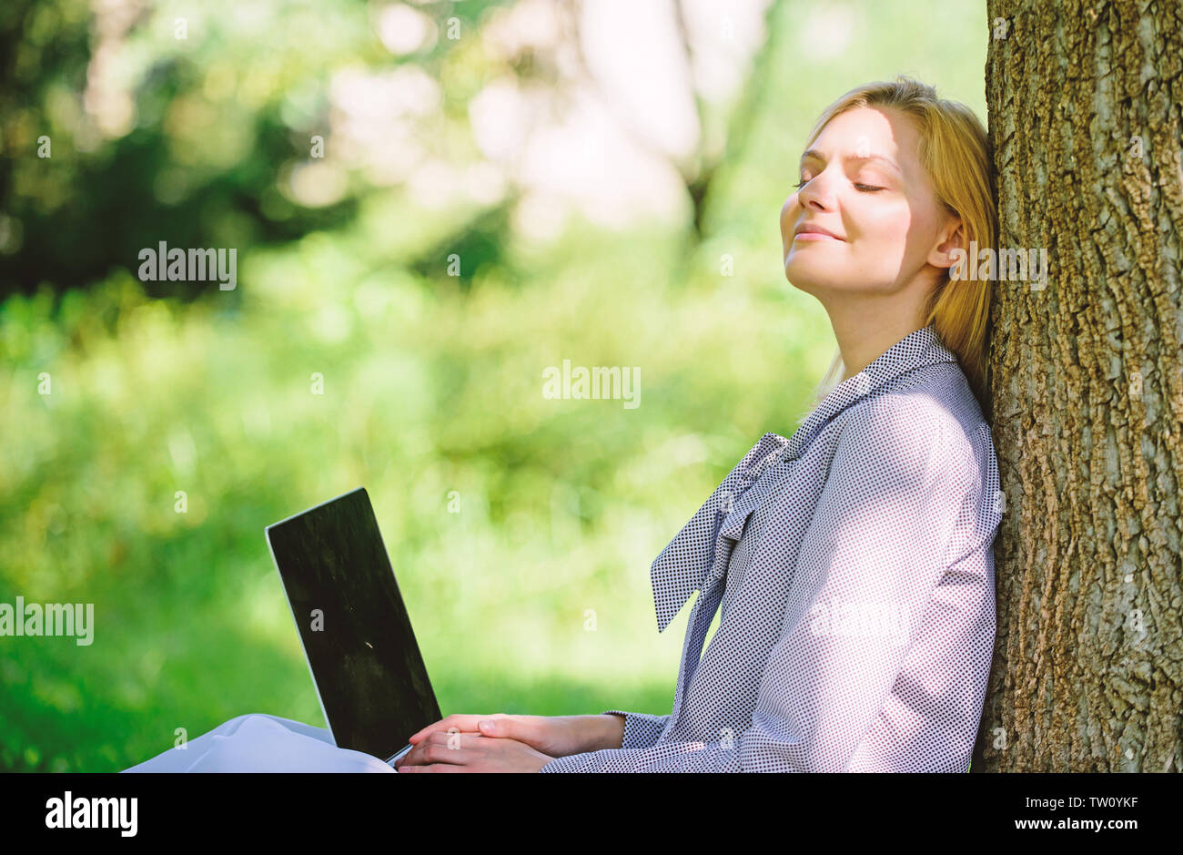 Girl work with laptop in park sit on grass. Natural environment office ...