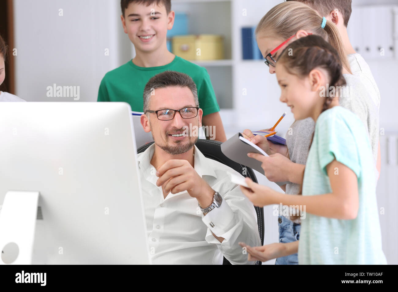 Male teacher working with computer while conducting lesson in classroom ...