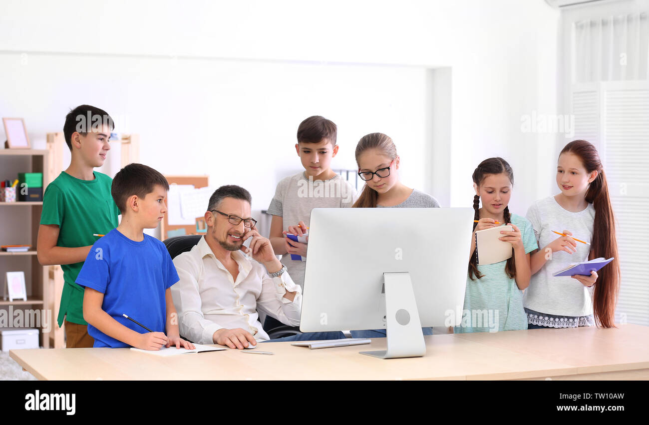 Male teacher working with computer while conducting lesson in classroom ...