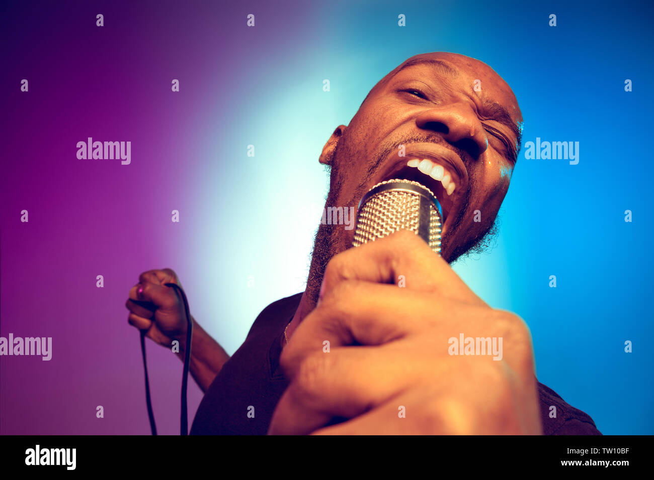 Young african-american jazz musician singing a song on gradient purple ...