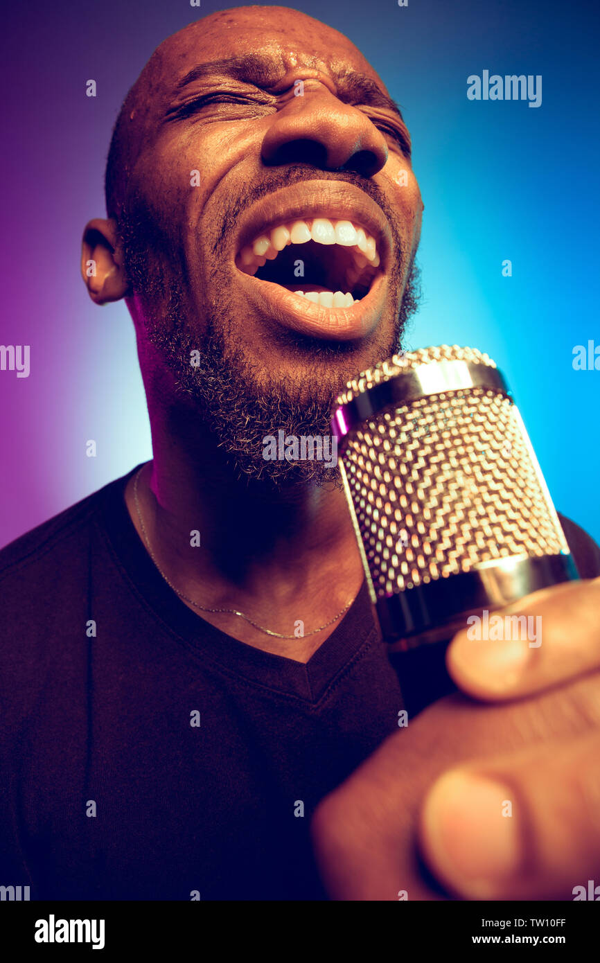 Young african-american jazz musician singing a song on gradient purple ...