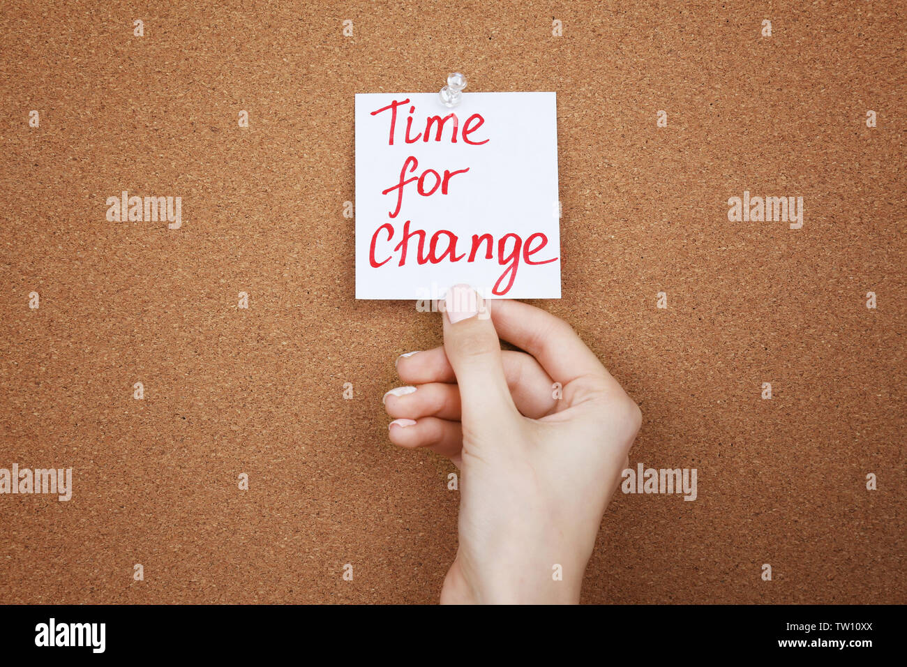 Female hand holding note with phrase TIME FOR CHANGE on cork board ...