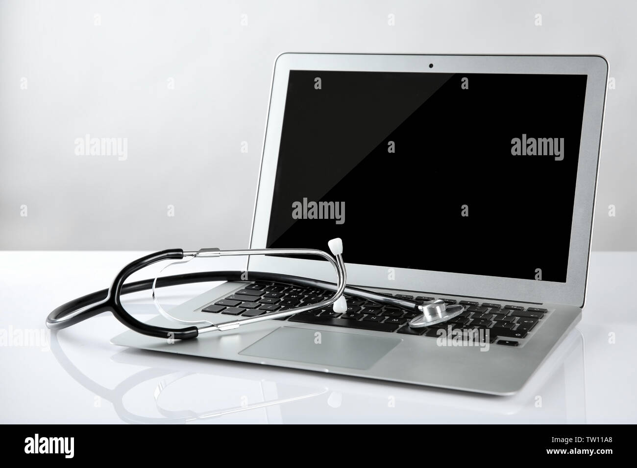 Laptop and stethoscope on white table Stock Photo - Alamy
