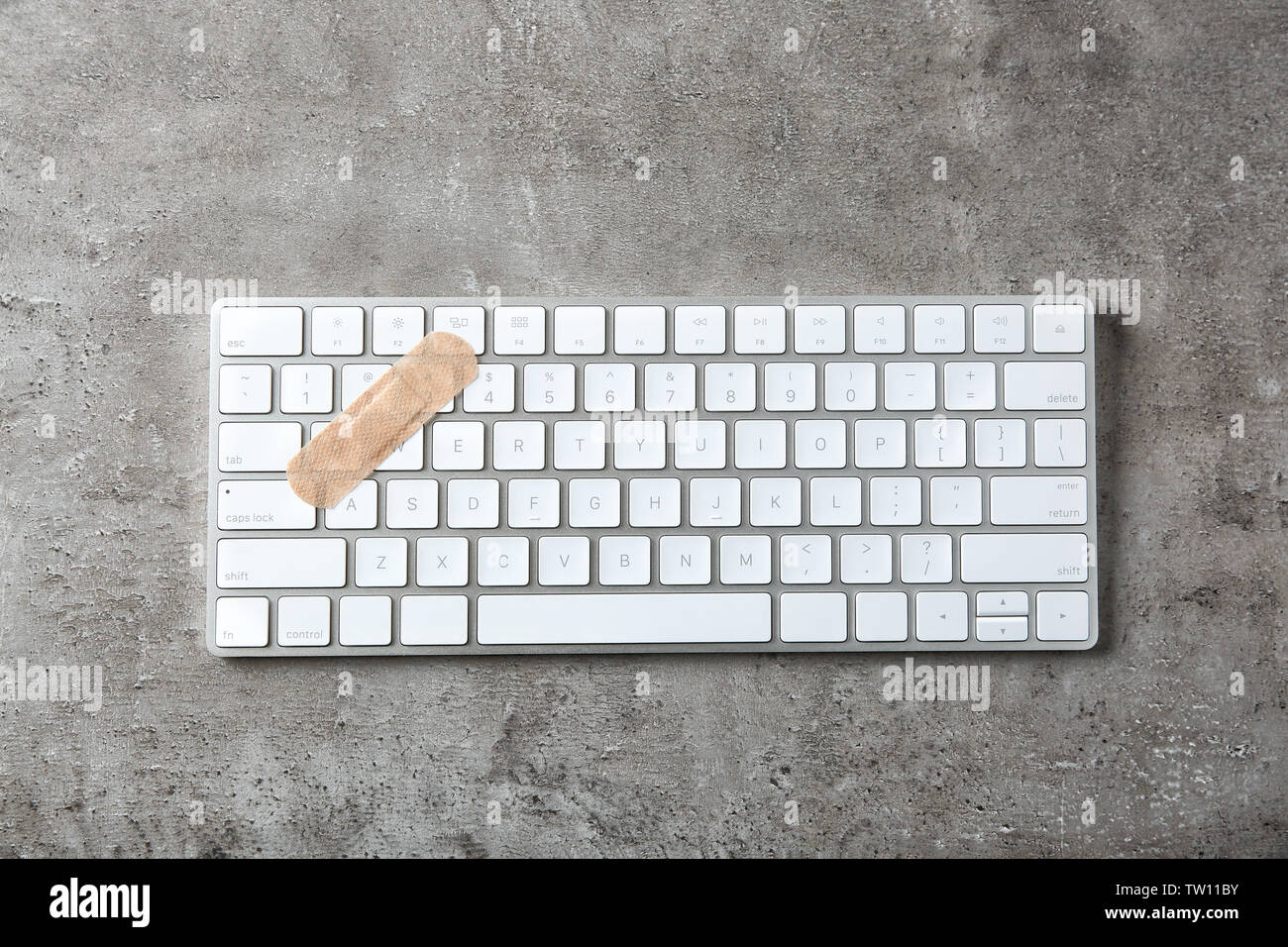 Computer keyboard with adhesive bandage on grey table Stock Photo - Alamy
