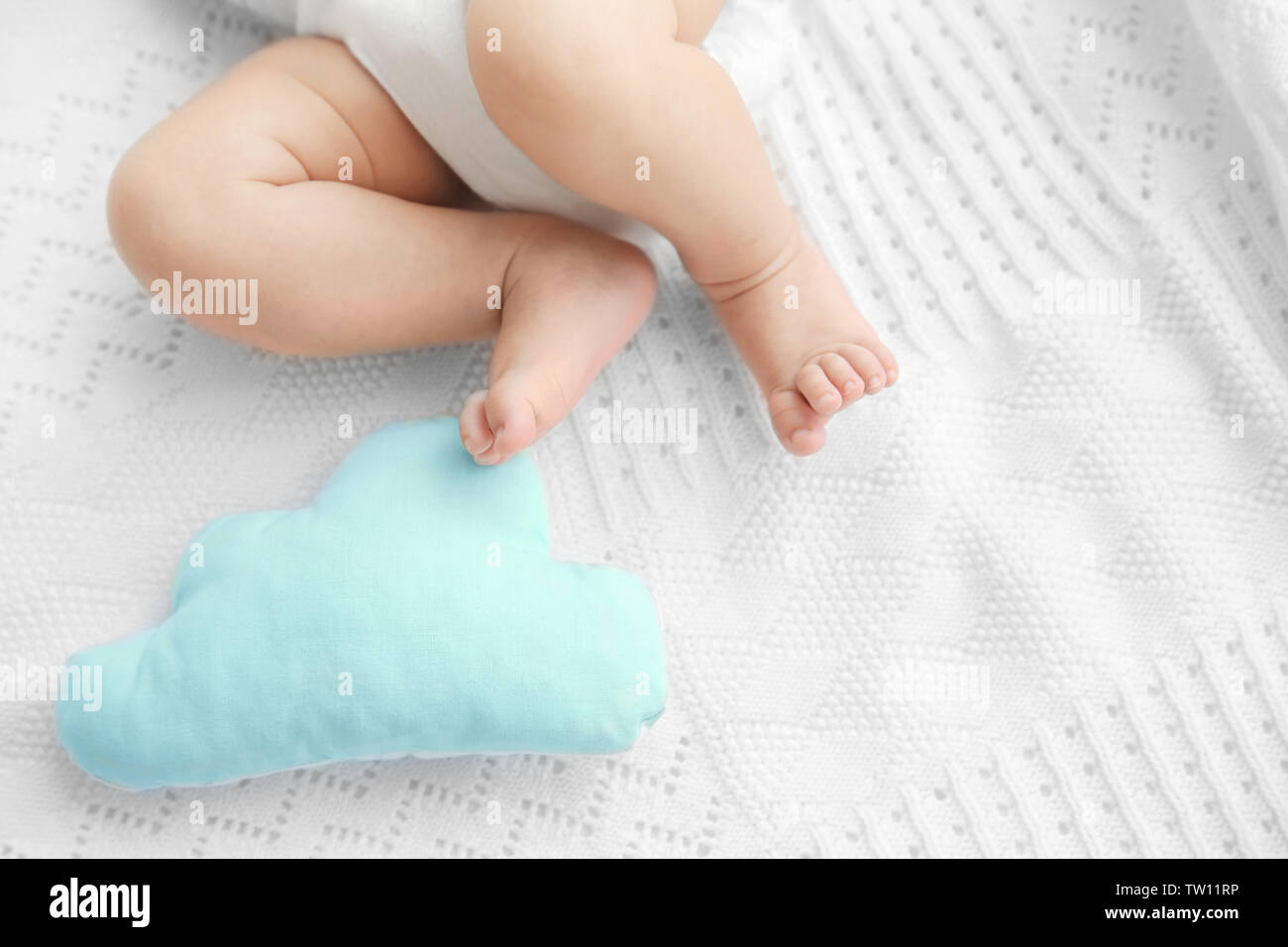 Little baby legs on bed with toy Stock Photo - Alamy