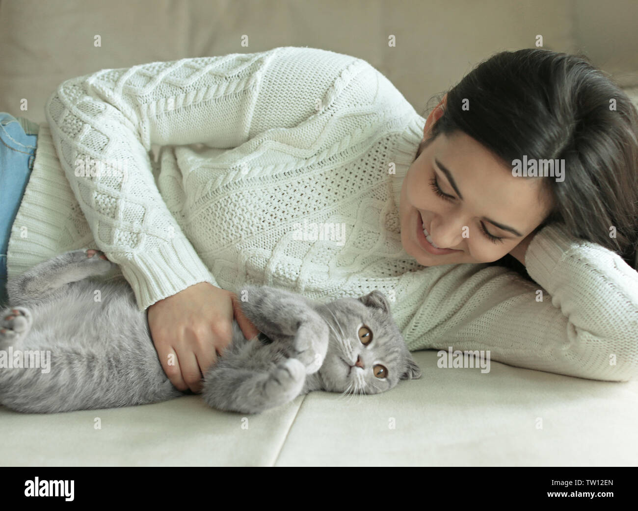 Beautiful young woman with cute cat resting at home Stock Photo - Alamy