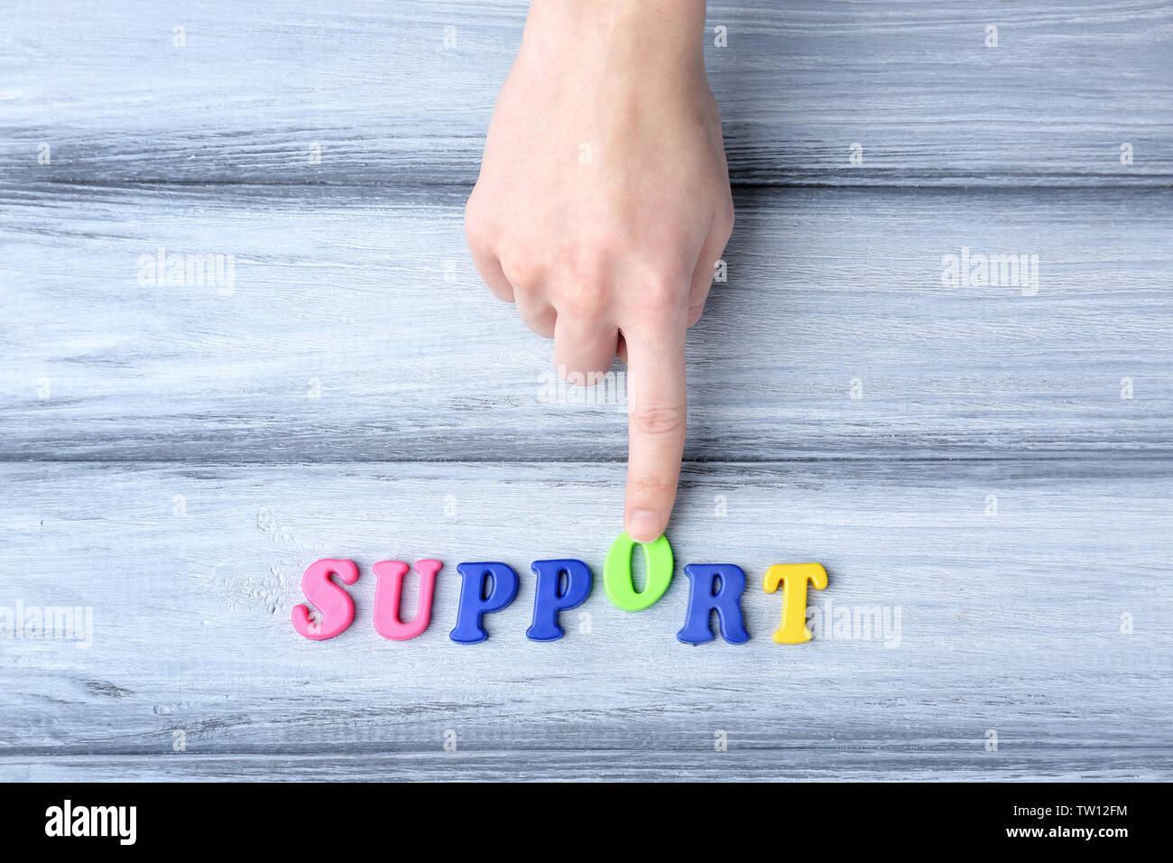 Hand adding letter O to word SUPPORT made of color plastic letters on ...