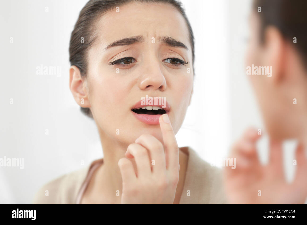 Beautiful woman applying cream onto lips near mirror Stock Photo - Alamy