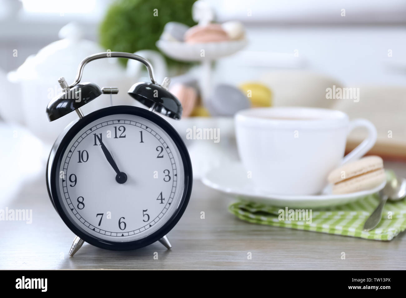 Retro alarm clock showing five minutes to eleven on lunch table Stock ...