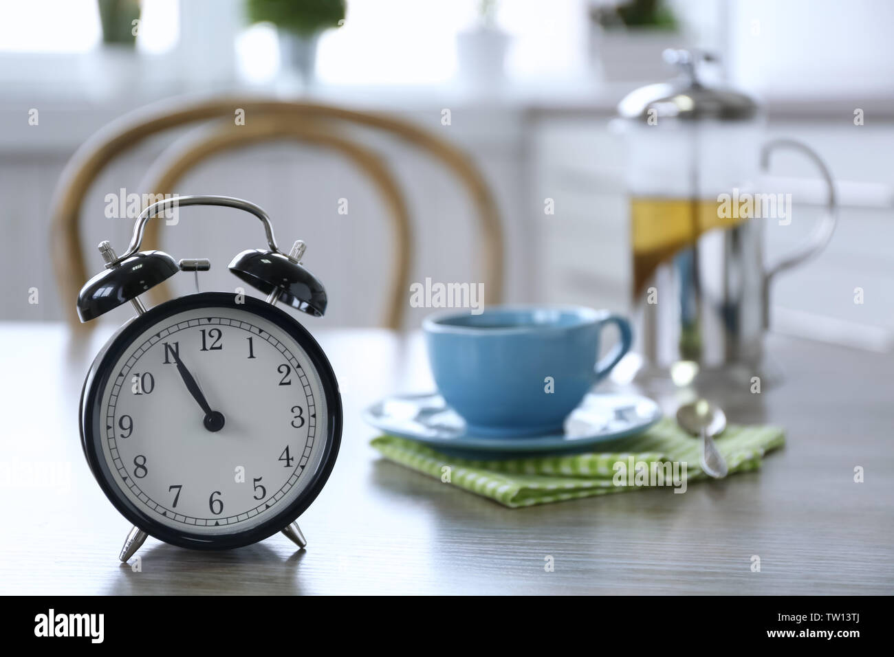 Retro alarm clock showing five minutes to eleven on lunch table Stock ...
