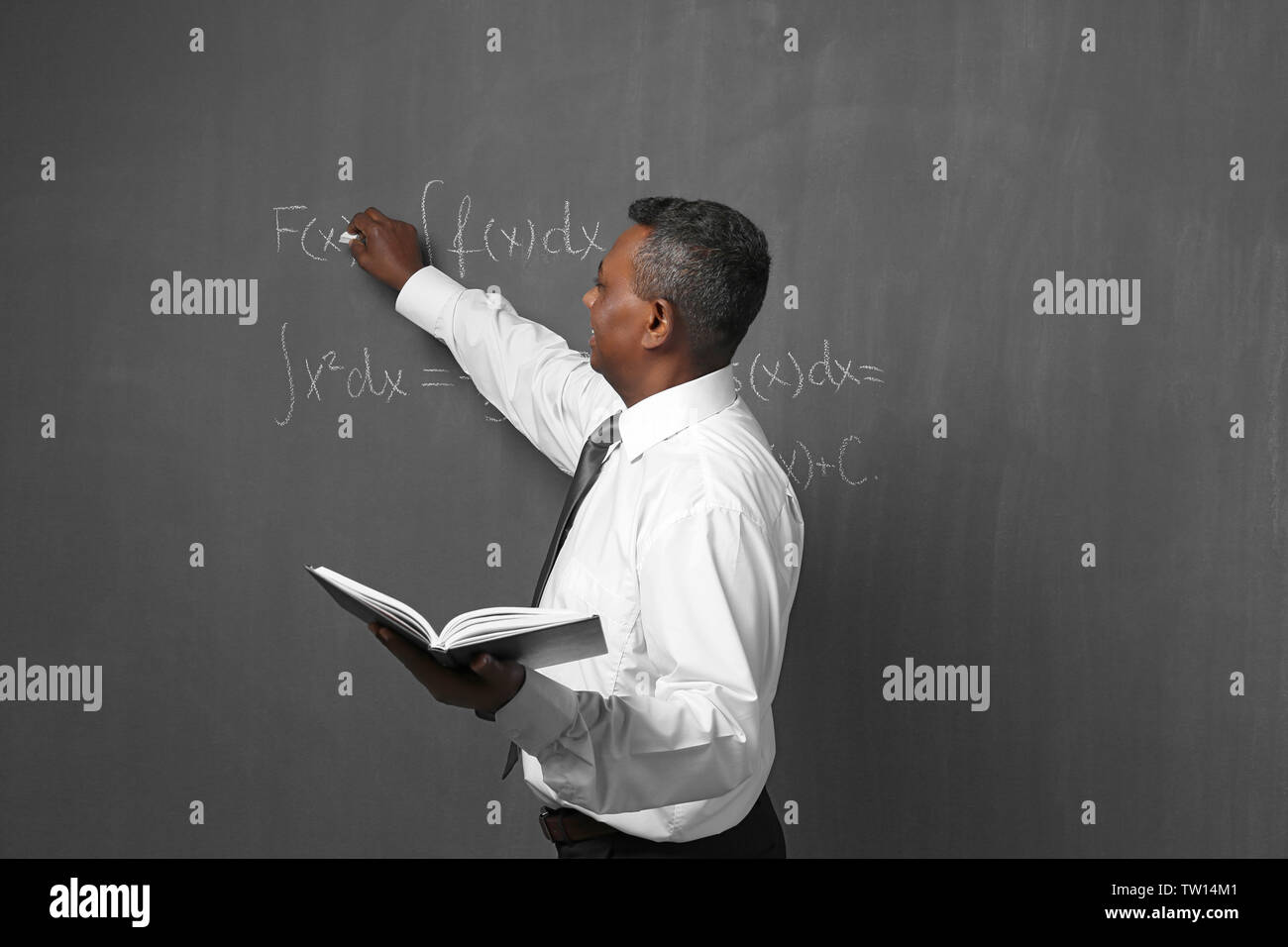 Confident Indian teacher writing math formulas on blackboard Stock ...